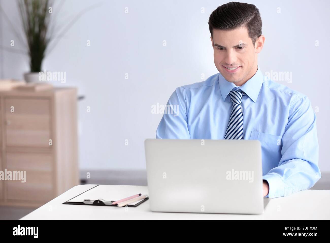 Young man in office wear using laptop indoors Stock Photo - Alamy