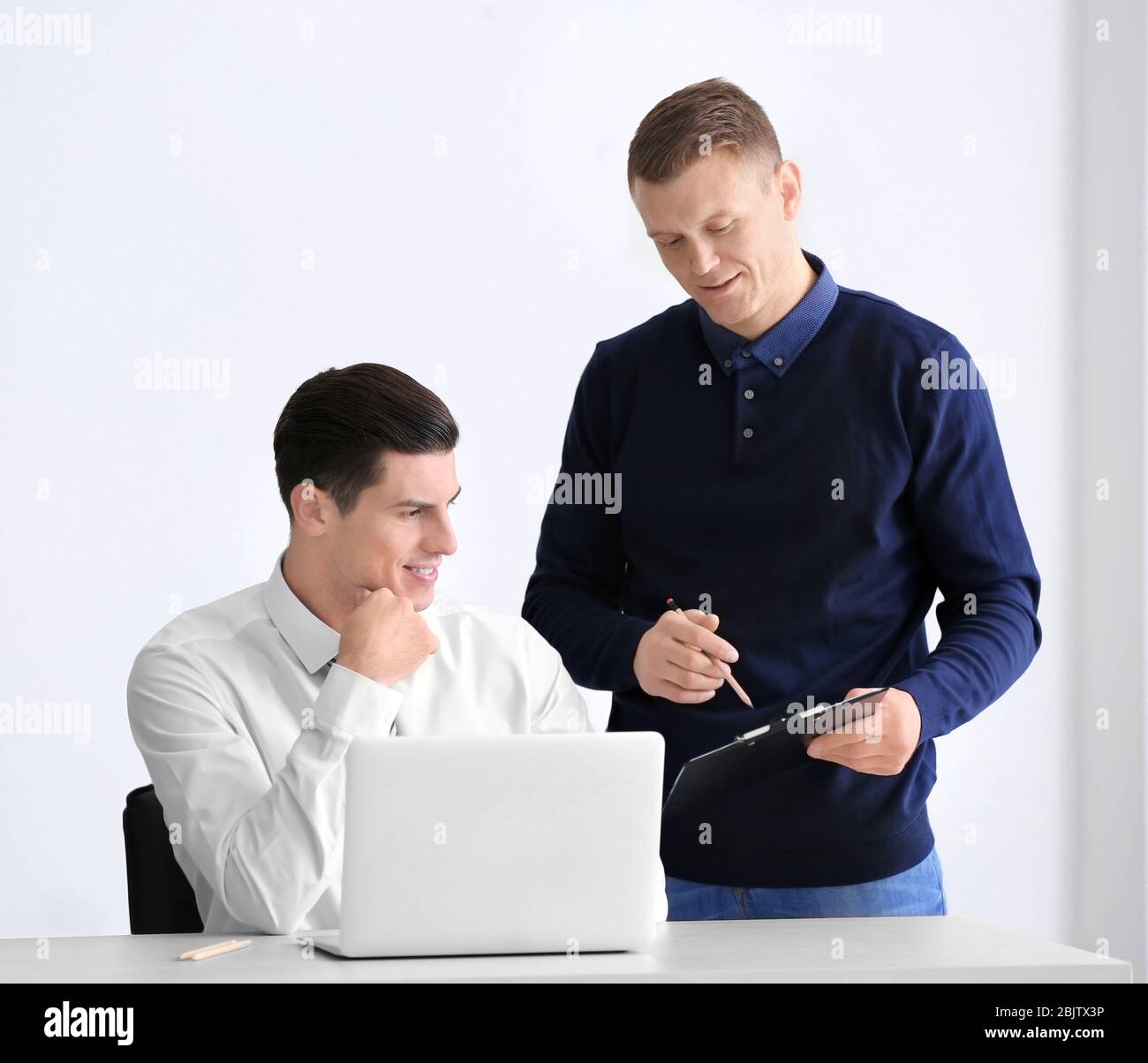 Young men with laptop on light background Stock Photo - Alamy