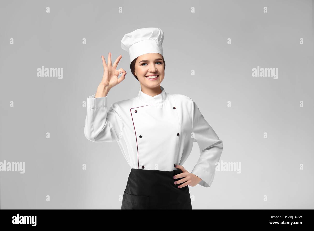 Portrait of female chef on grey background Stock Photo - Alamy