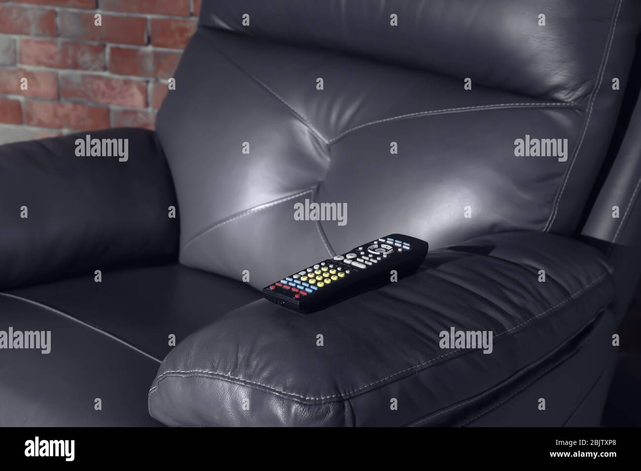 Leather armchair with remote control in home cinema, closeup. Watching ...