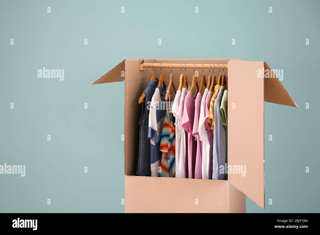Wardrobe box with clothes on color background Stock Photo - Alamy