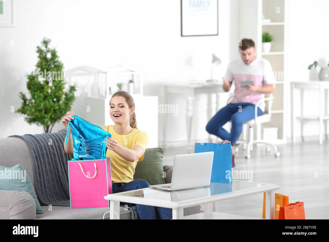 Woman with shopping bags and unhappy man at home. Money problems in ...