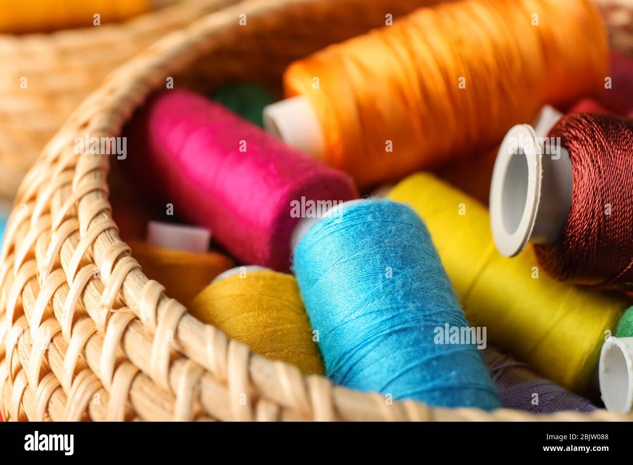Wicker box with color sewing threads, closeup Stock Photo - Alamy