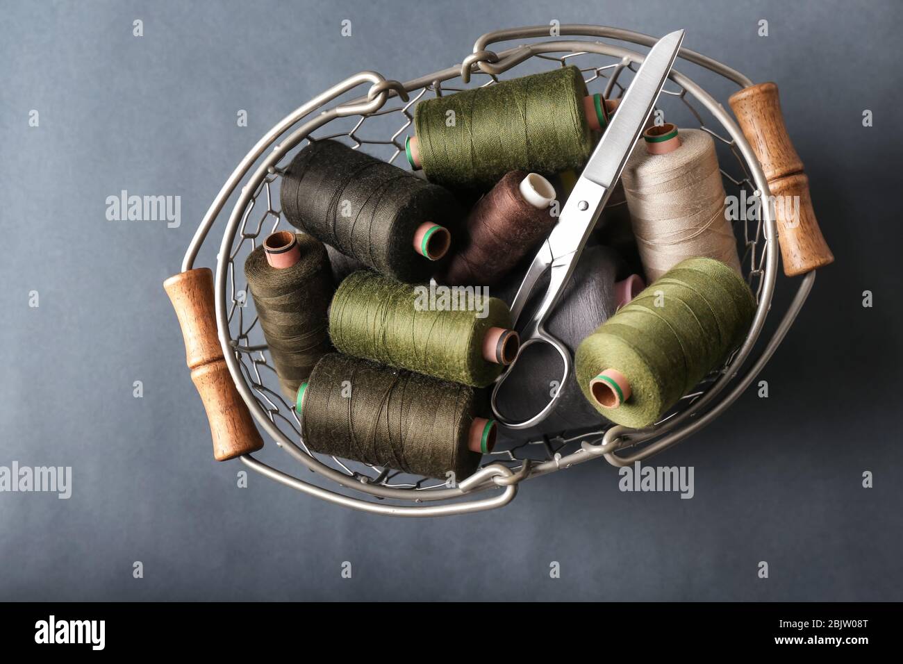 Metal basket with color sewing threads on grey background Stock Photo ...