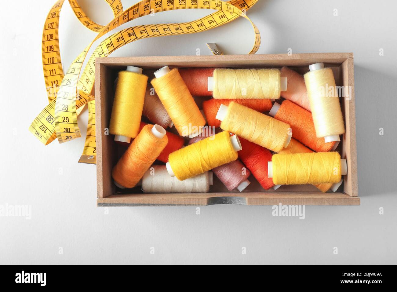 Box with color sewing threads on light background, top view Stock Photo ...