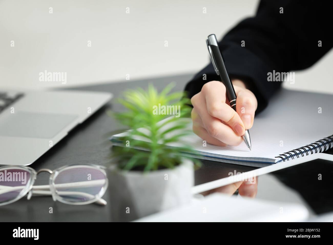 Female student writing in notebook at table, closeup. Studying process ...
