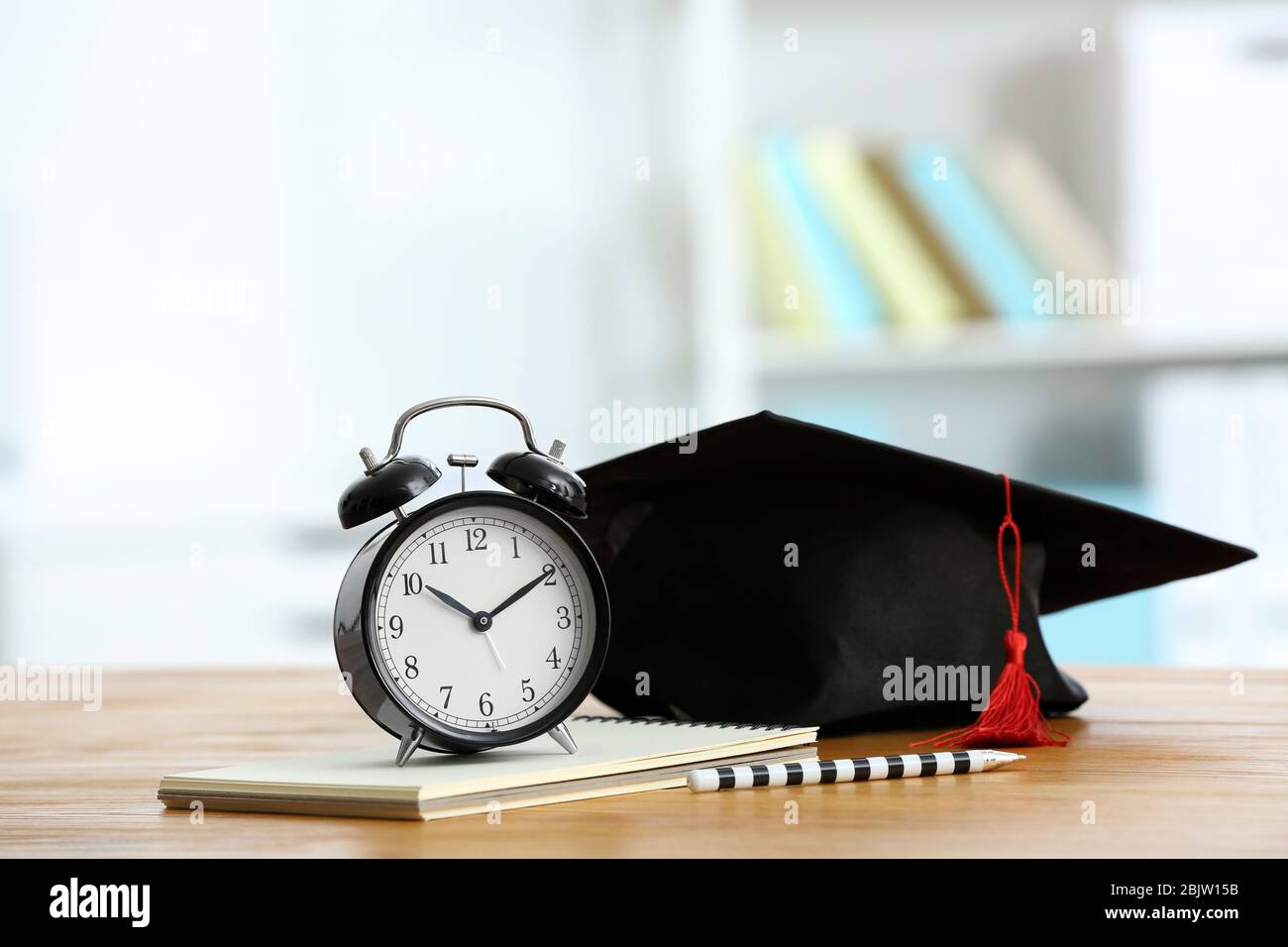 Alarm clock and graduation cap on table. Study goals Stock Photo - Alamy