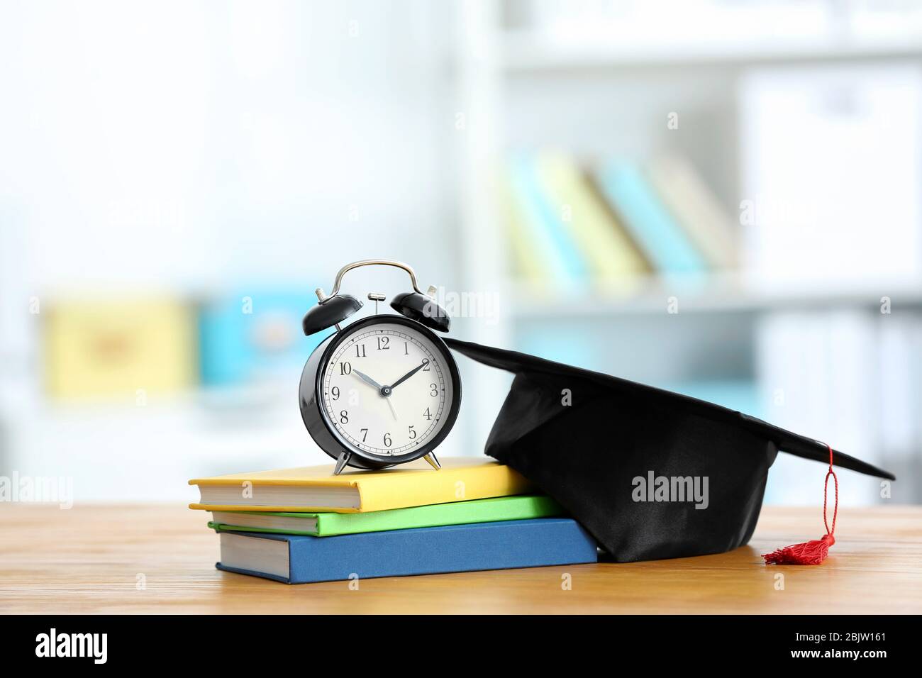 Alarm clock, graduation cap and textbooks on table. Study goals Stock ...