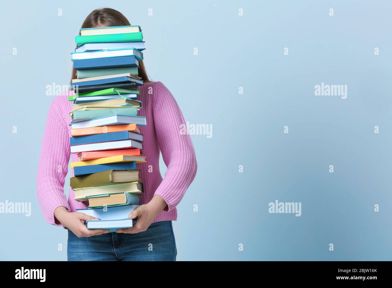 Student carrying stack of textbooks on color background. Studying ...