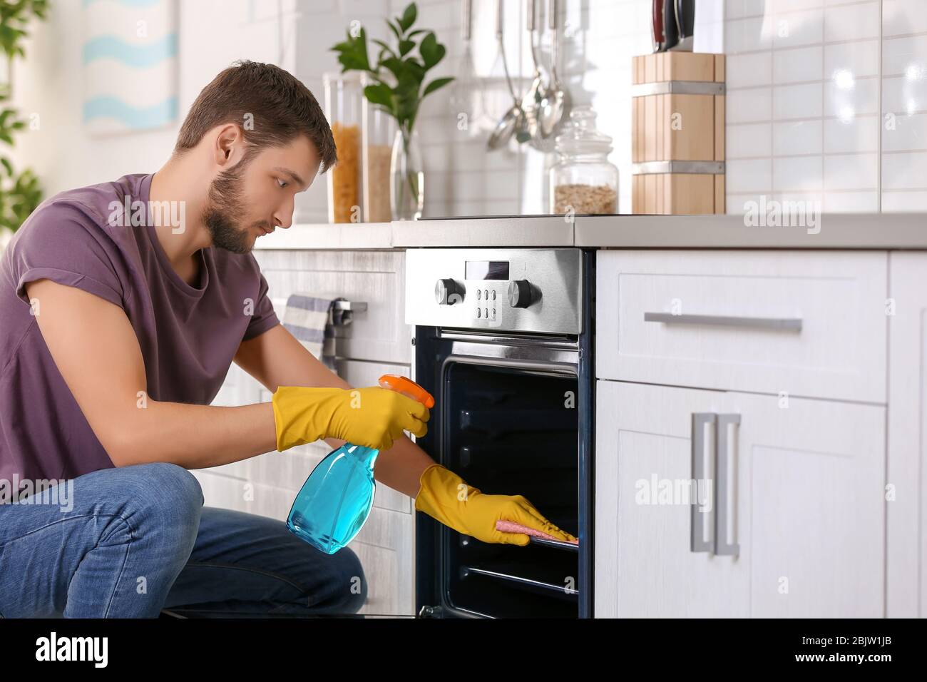 Young man cleaning oven in kitchen Stock Photo - Alamy