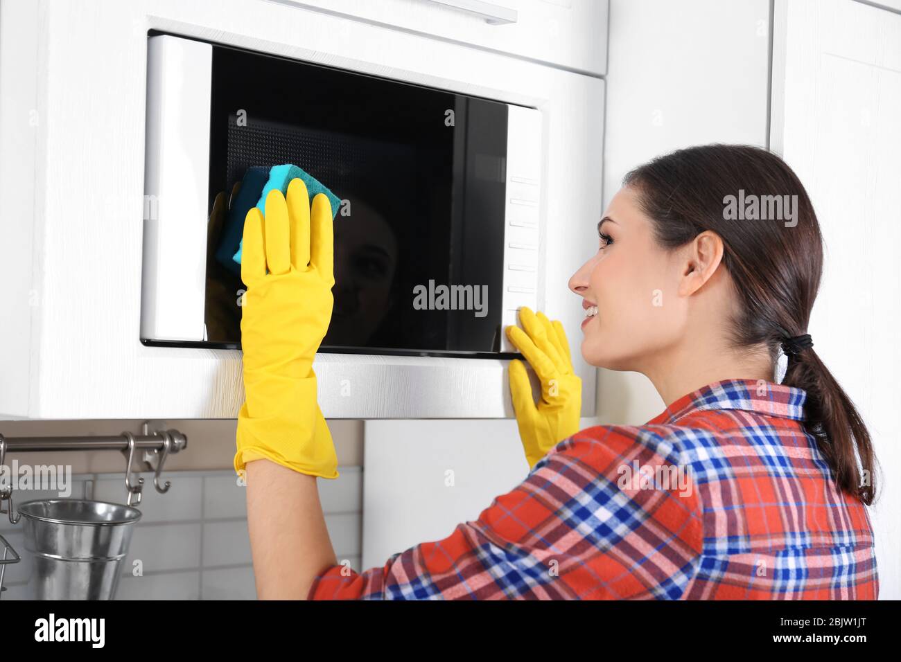 Young woman cleaning microwave oven in kitchen Stock Photo - Alamy
