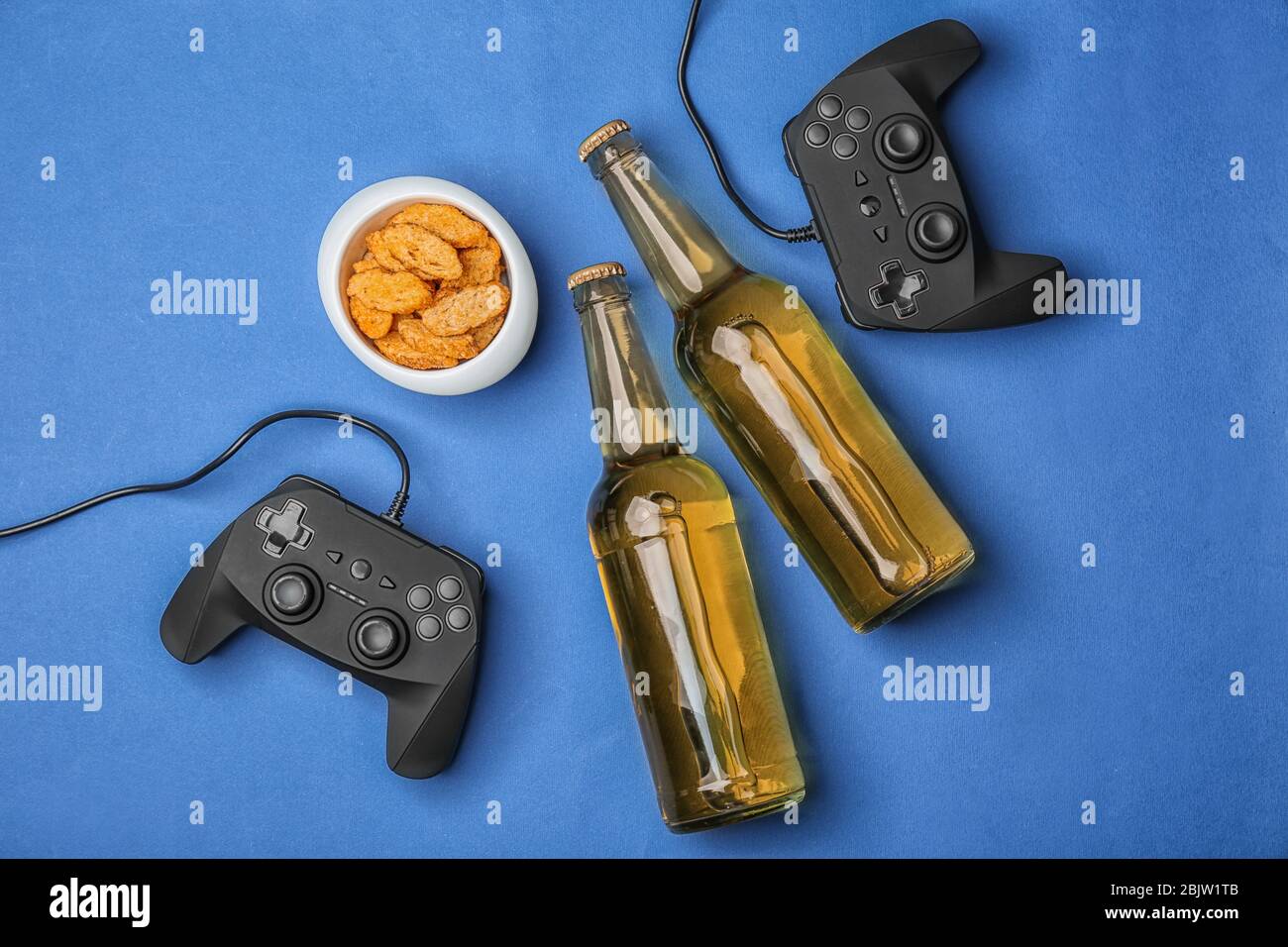 Composition with video game controllers, beer and snack on color ...