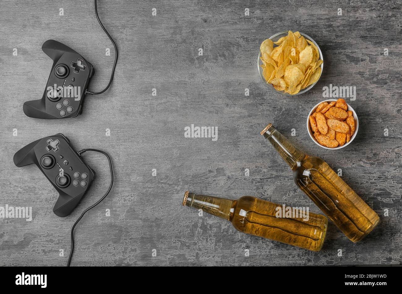 Composition with video game controllers, beer and snack on grey ...