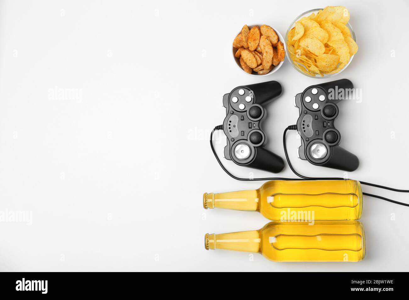 Composition with video game controllers, beer and snack on light ...