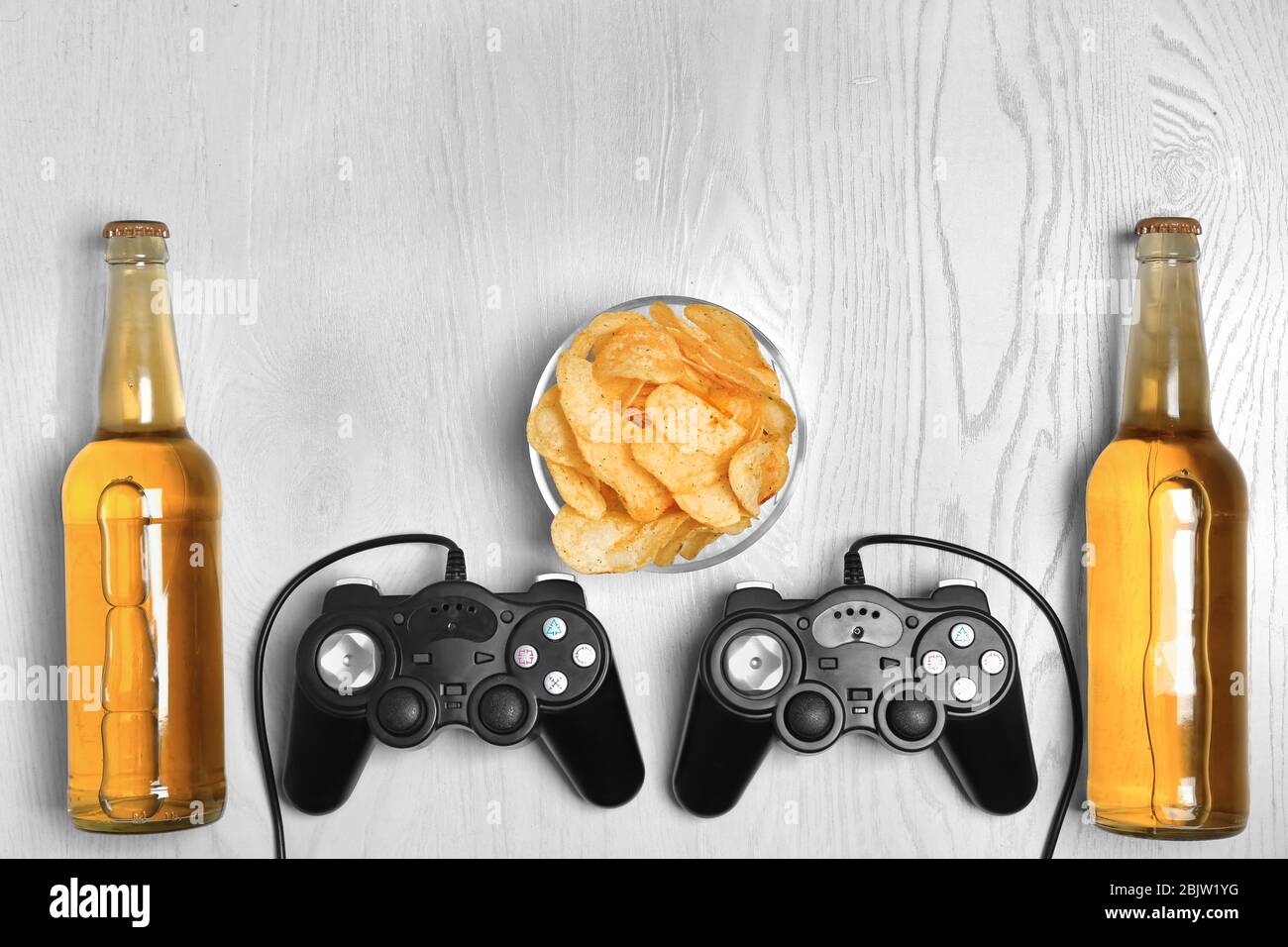 Composition with video game controllers, beer and snack on light ...