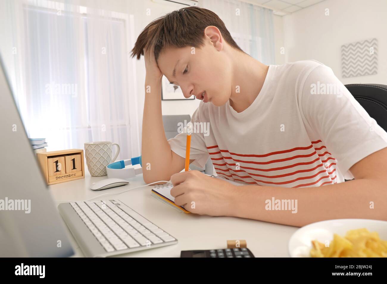 Tired teenager boy doing homework indoors Stock Photo - Alamy