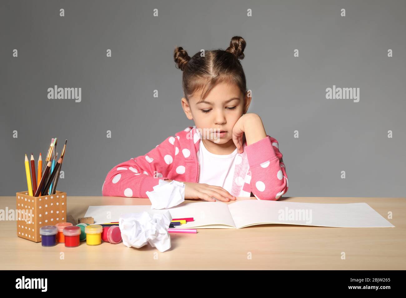 Cute little girl doing homework against grey background Stock Photo - Alamy