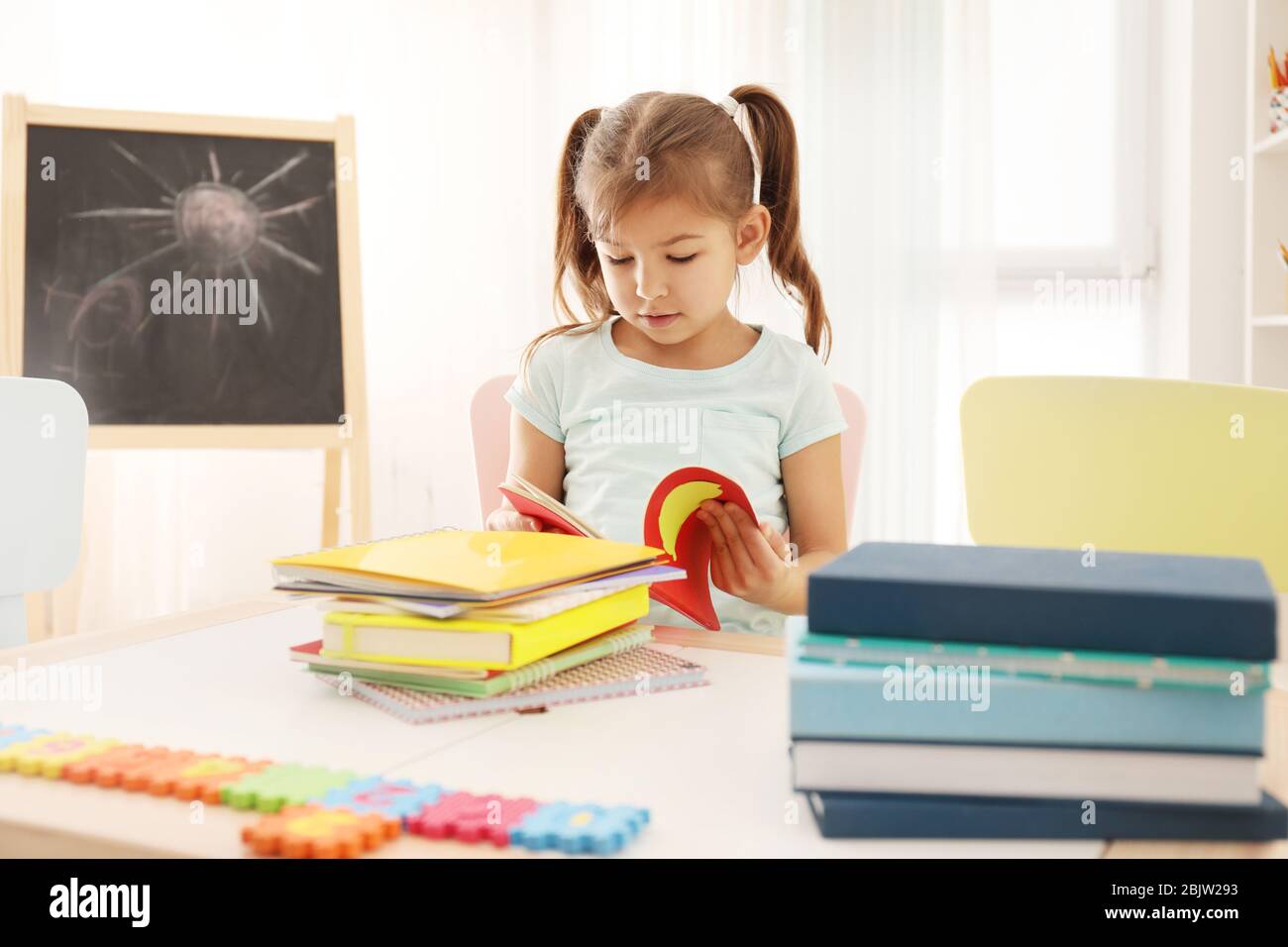 Cute little girl doing homework indoors Stock Photo - Alamy