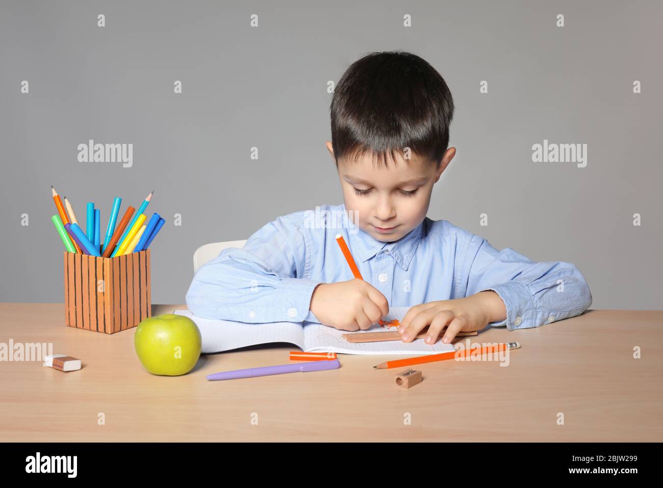 Cute little boy doing homework against grey background Stock Photo - Alamy
