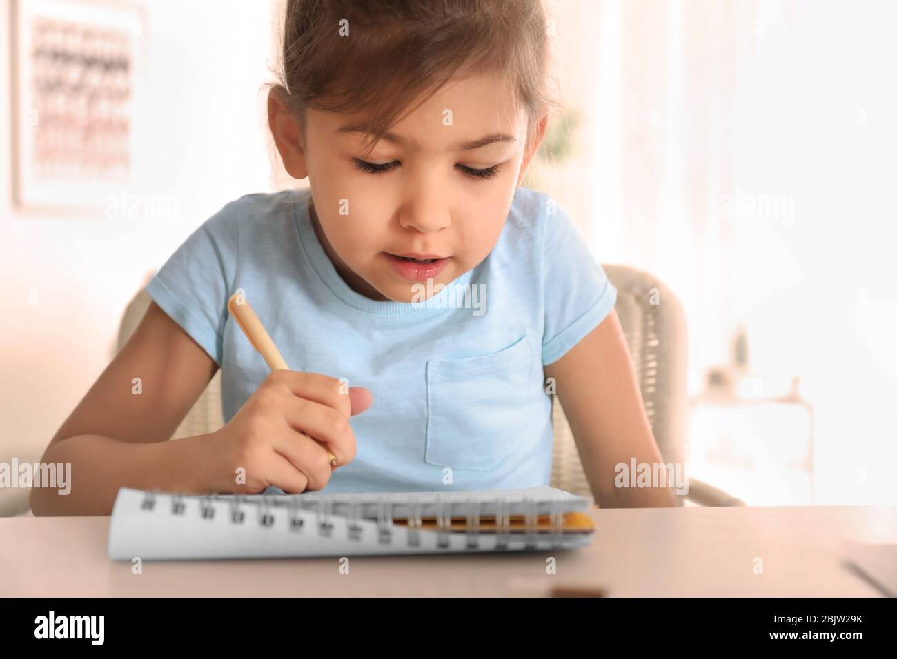 Cute little girl doing homework indoors Stock Photo - Alamy