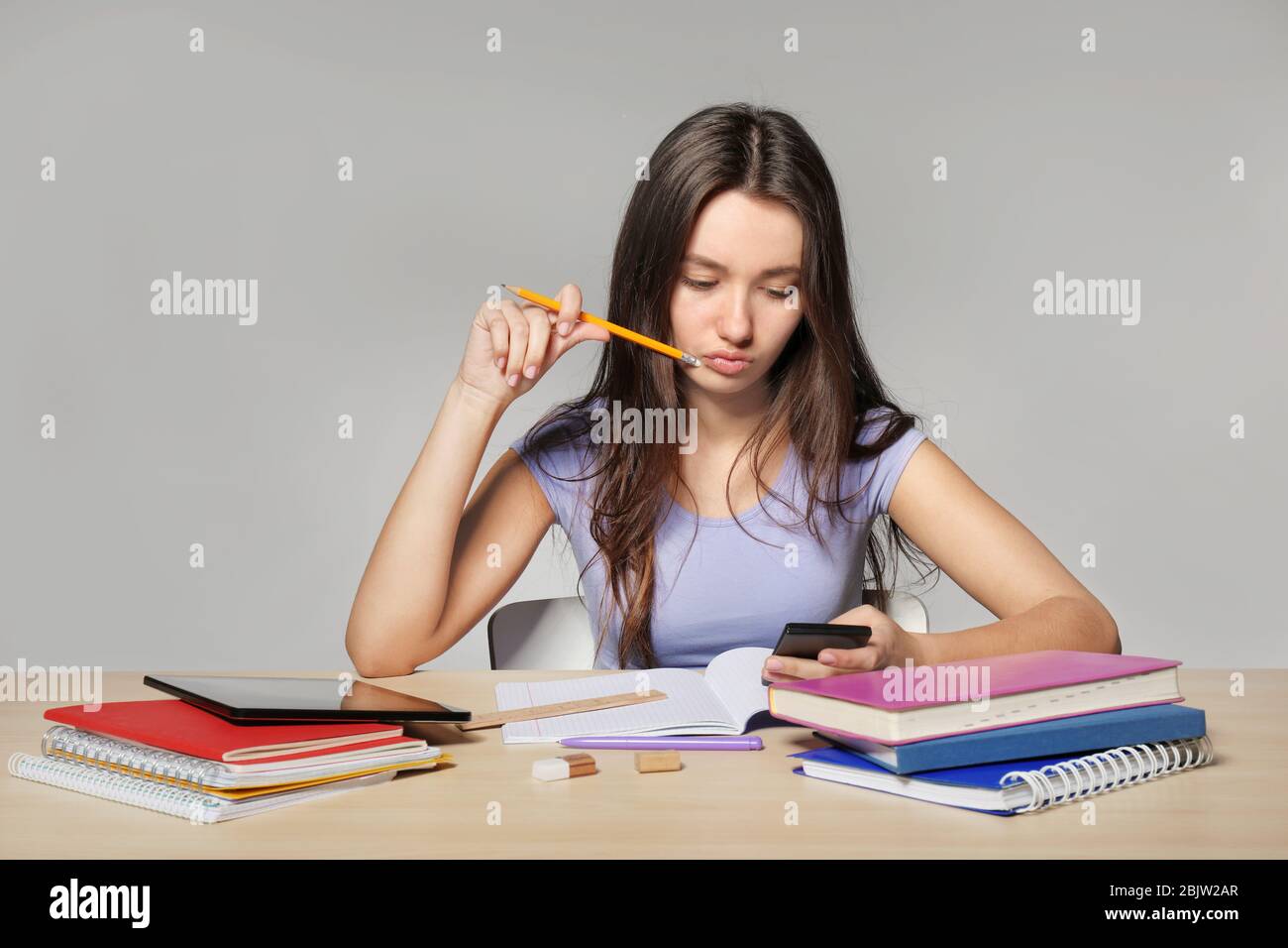 Cute teenager girl doing homework against grey background Stock Photo ...