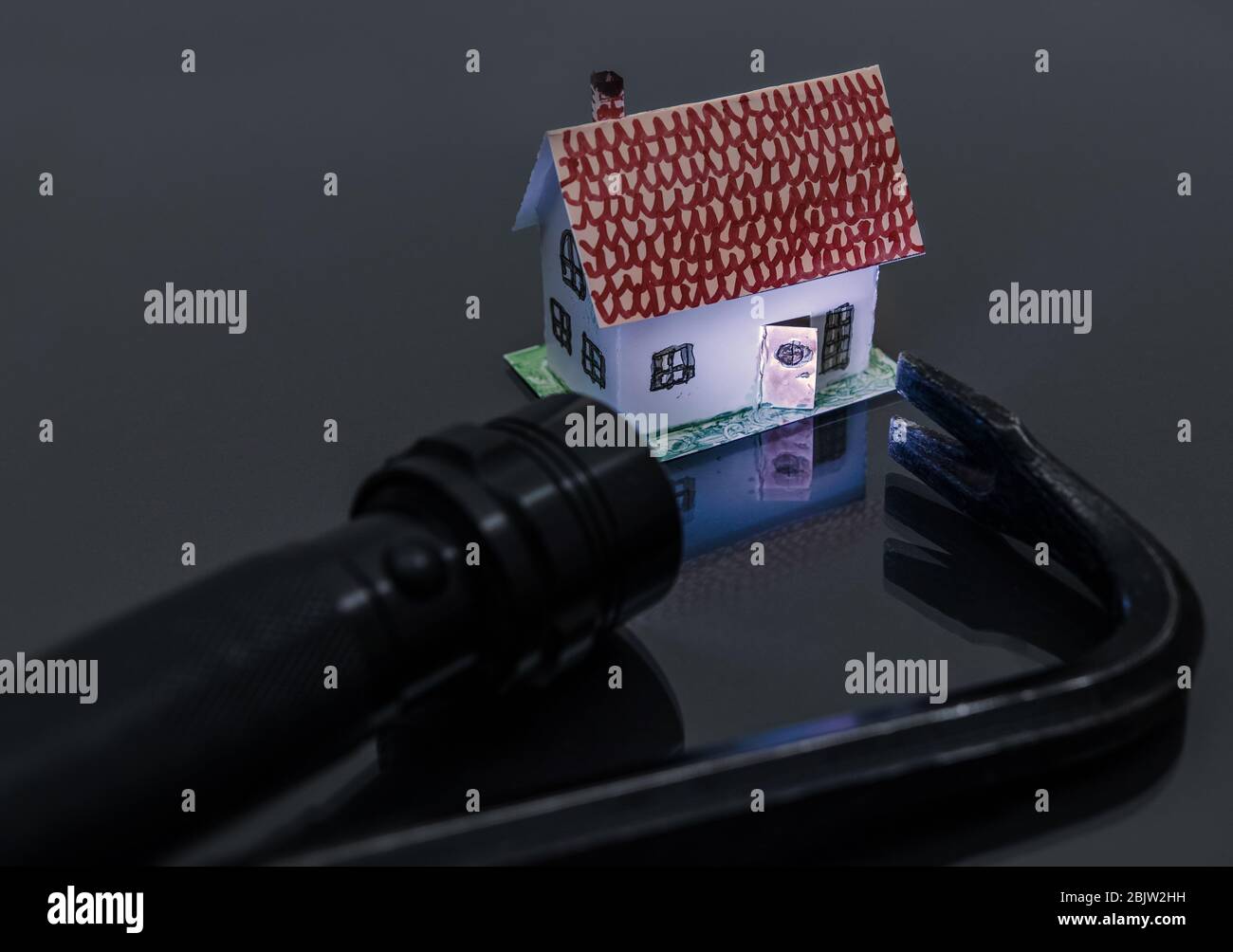 A tiny little house, a torch and a crowbar. The toy house is lit by the ...