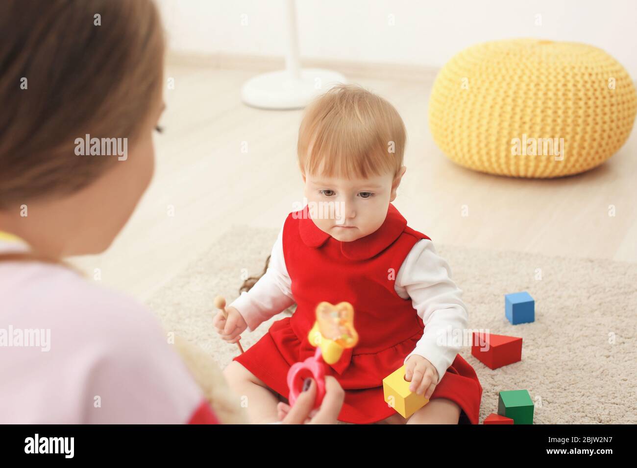 Cute little girl with young nanny, indoors Stock Photo - Alamy