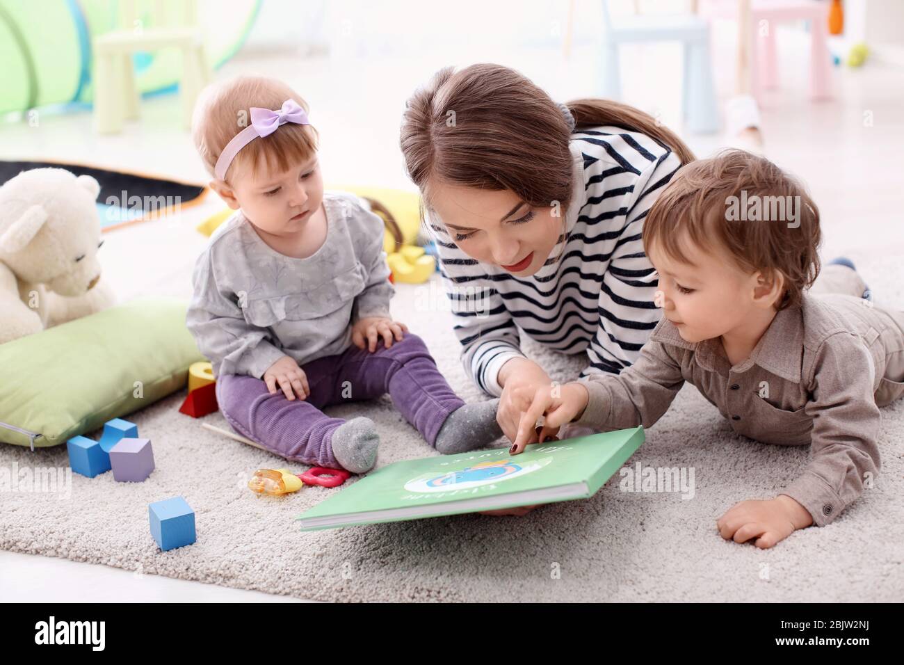 Young nanny with cute little children, indoors Stock Photo - Alamy