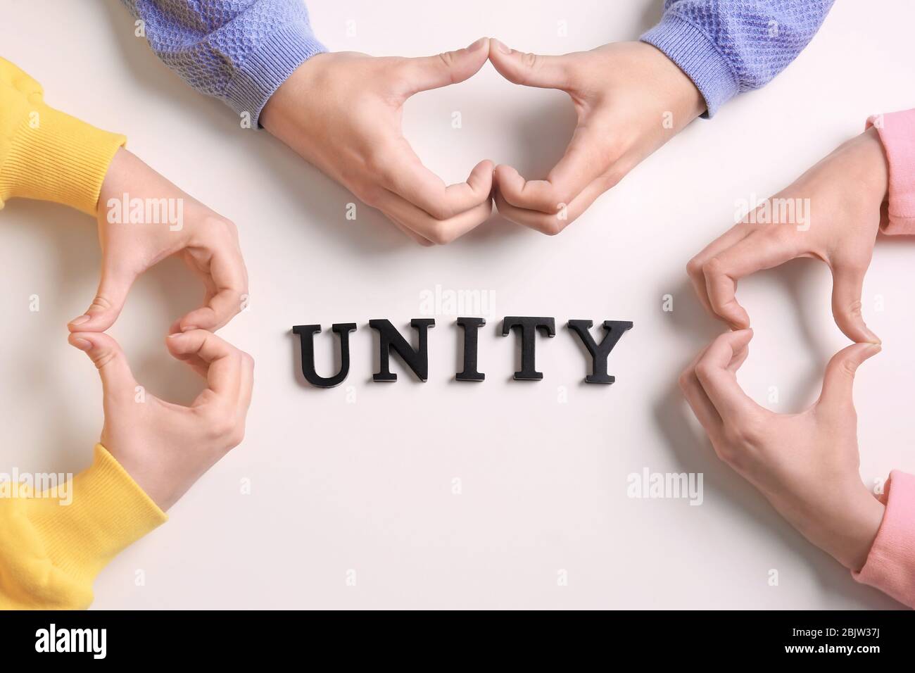 People making heart shape symbols with hands and word UNITY on white ...