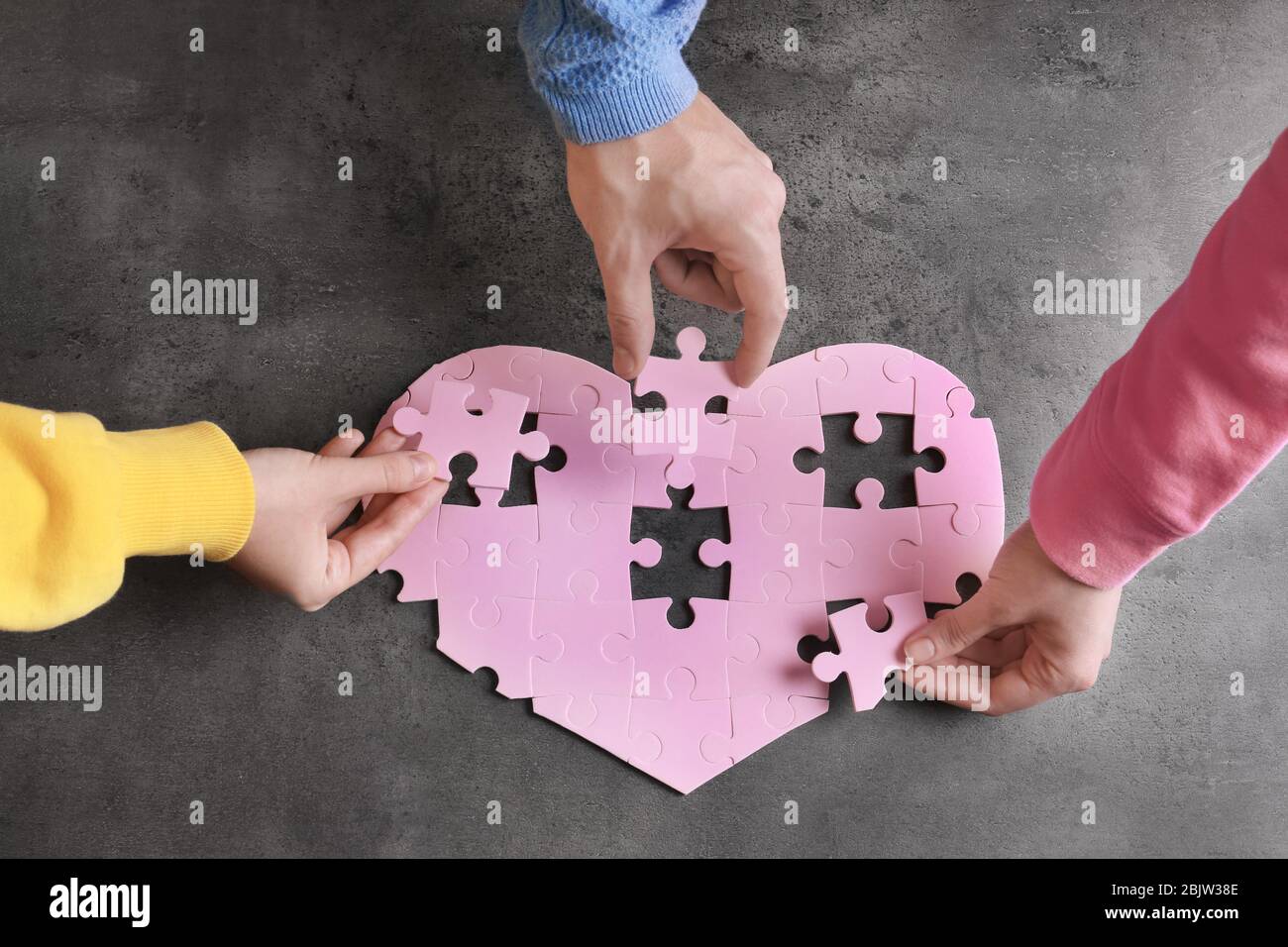 Group of people completing puzzle together on gray background. Unity ...