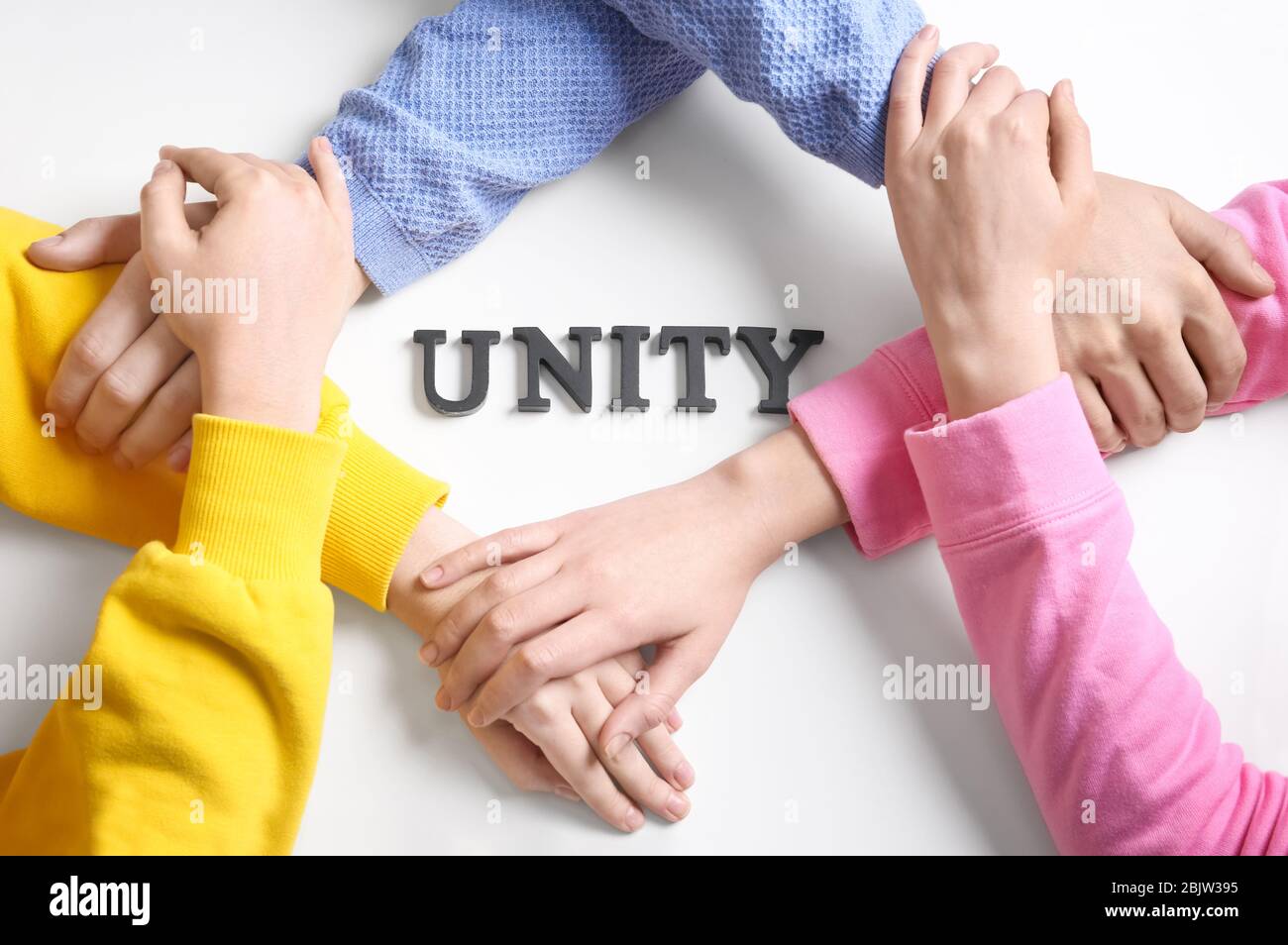 People holding hands together around word UNITY on white background ...
