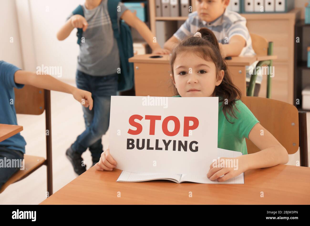 Little girl with sign "Stop bullying" in classroom Stock Photo - Alamy