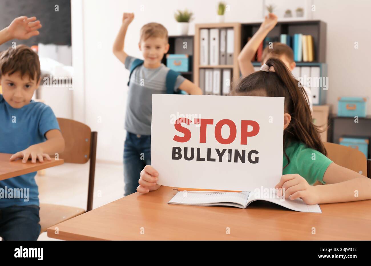 Little girl with sign "Stop bullying" in classroom Stock Photo - Alamy