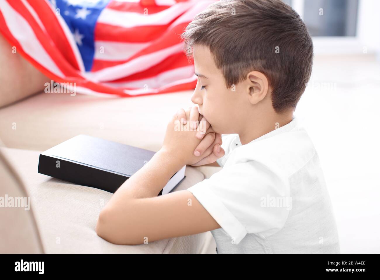 Little boy praying for America over closed Bible indoors Stock Photo ...