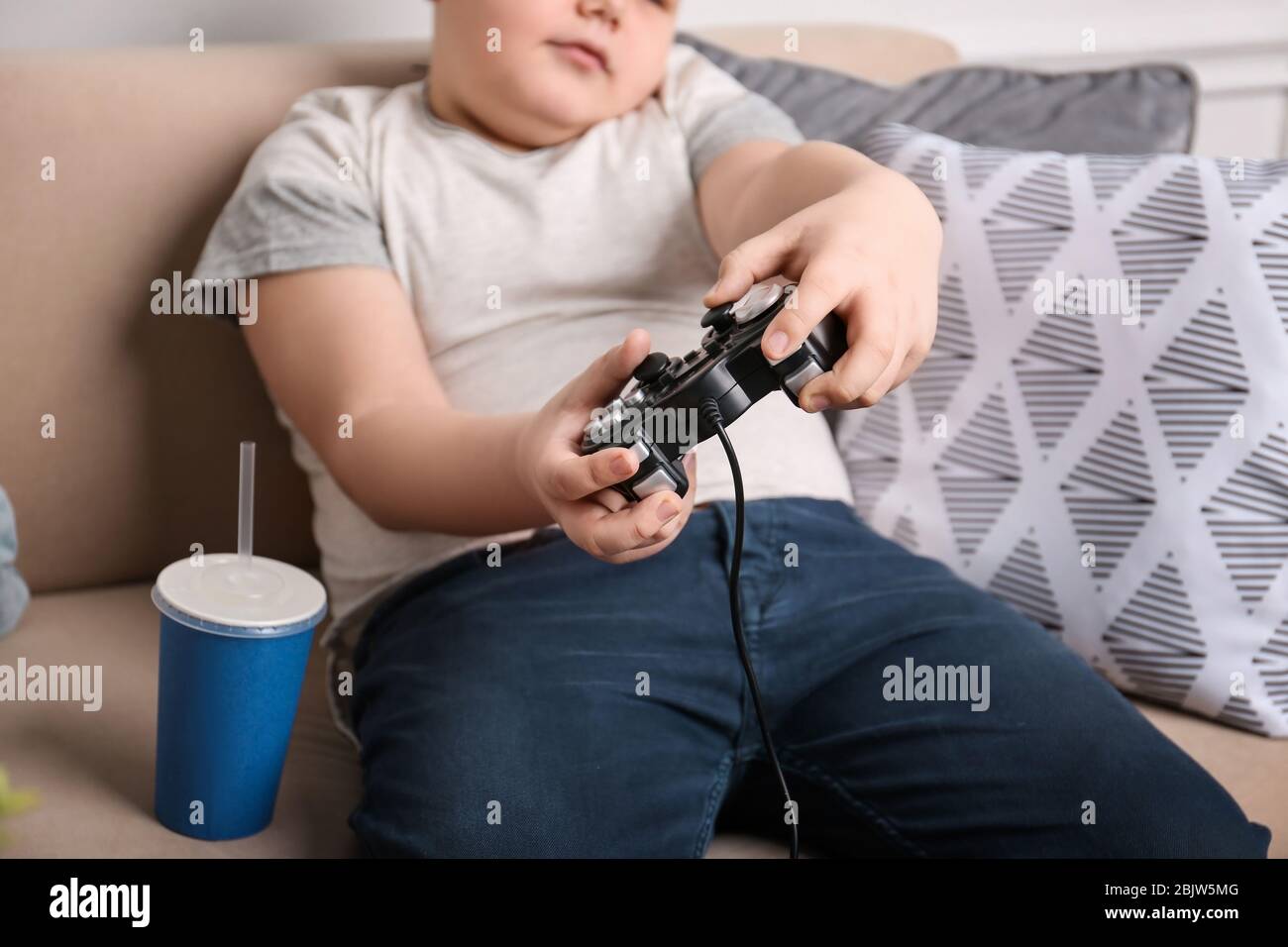 Overweight boy playing videogame indoors Stock Photo - Alamy