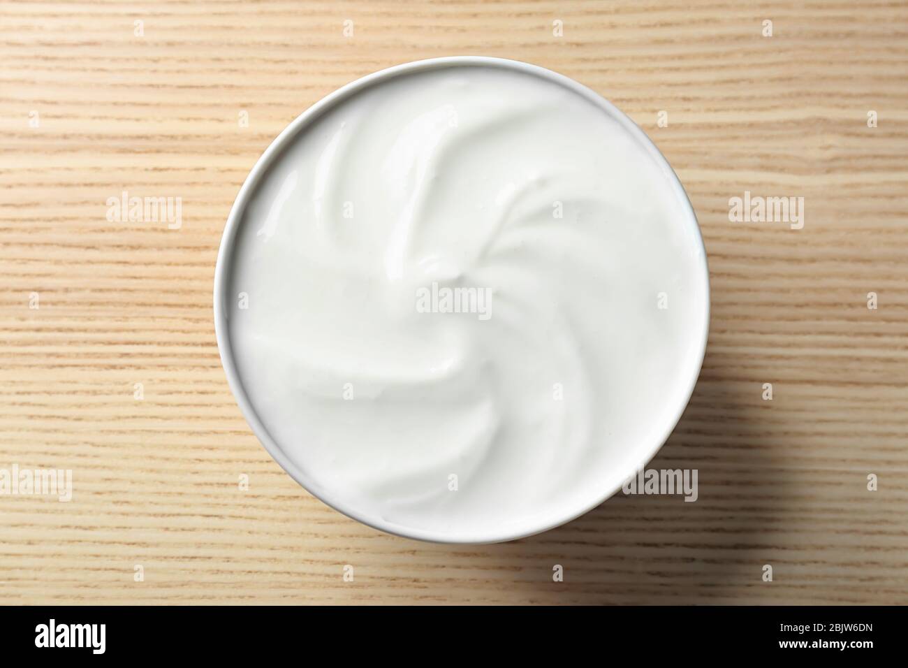 Tasty yogurt in dish on wooden table Stock Photo - Alamy
