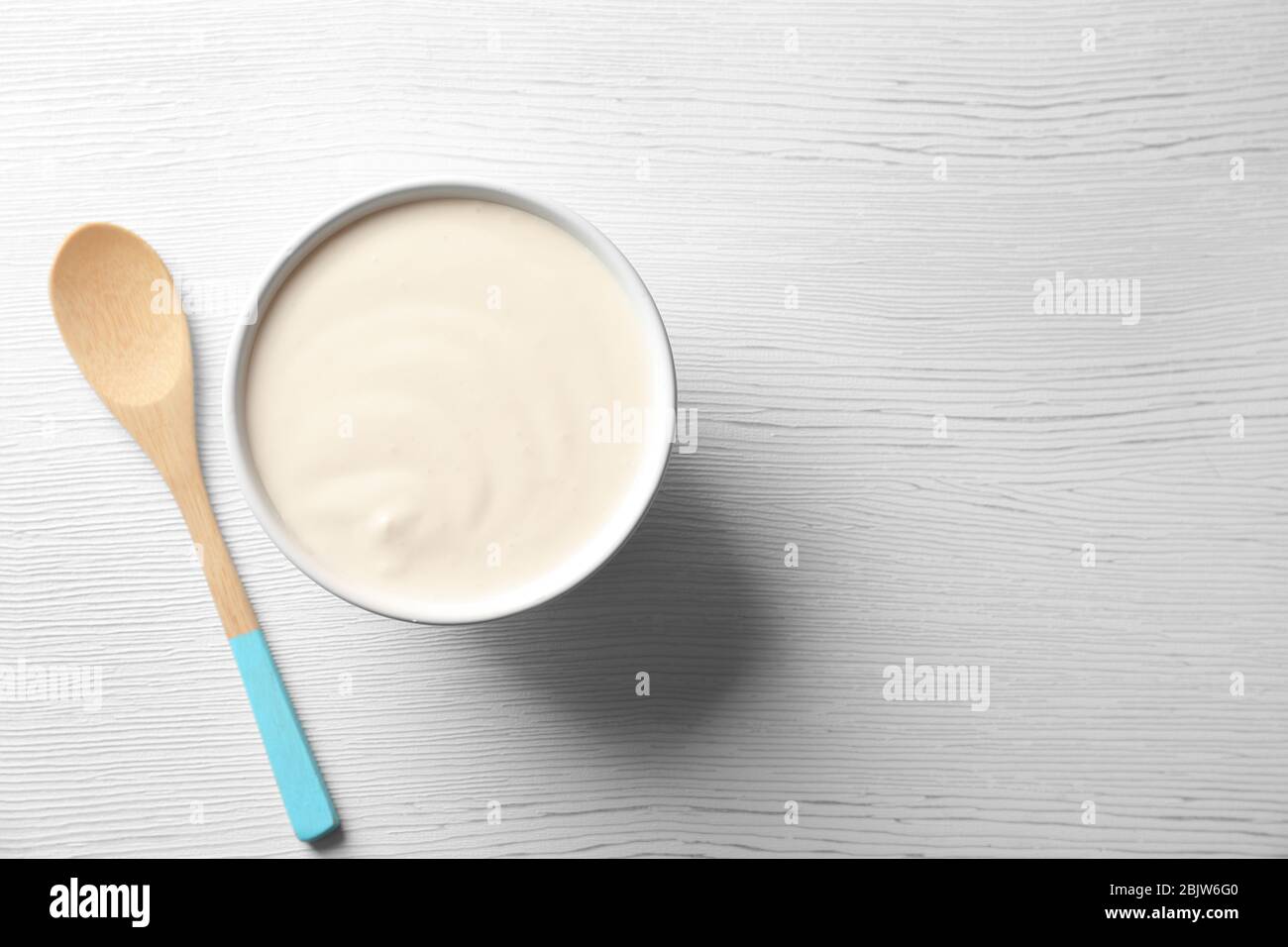 Tasty yogurt in dish on wooden table Stock Photo - Alamy