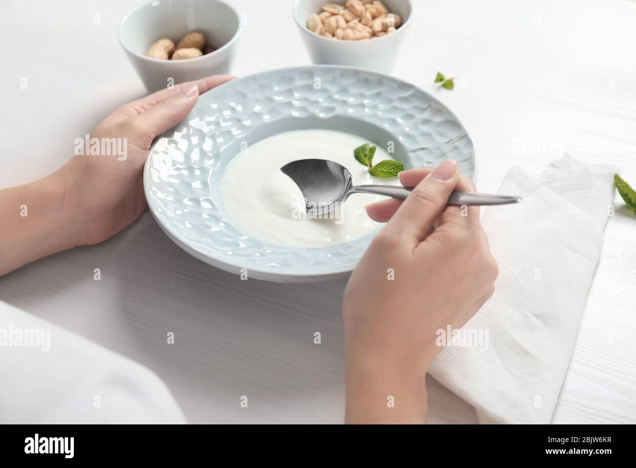 Woman eating tasty yogurt at wooden table Stock Photo - Alamy