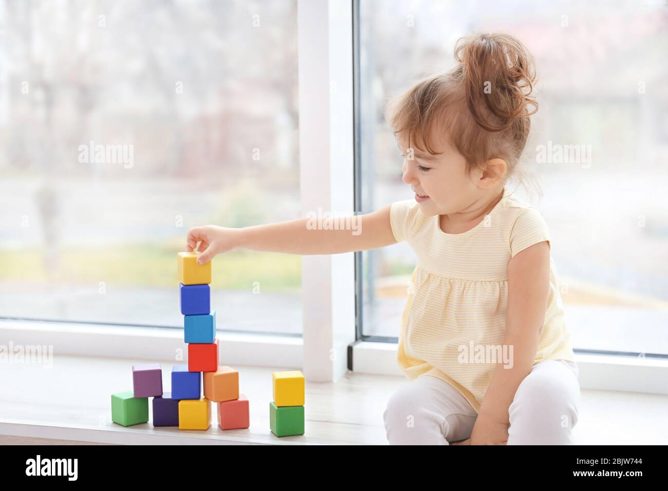 Adorable little girl playing with blocks indoors Stock Photo - Alamy
