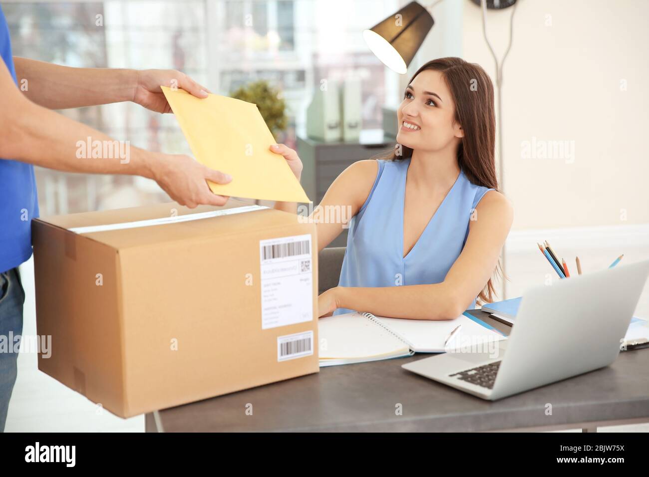 Woman receiving parcels from courier indoors Stock Photo - Alamy