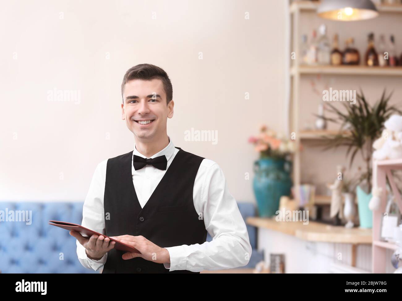 Attractive young waiter with menu at workplace Stock Photo - Alamy