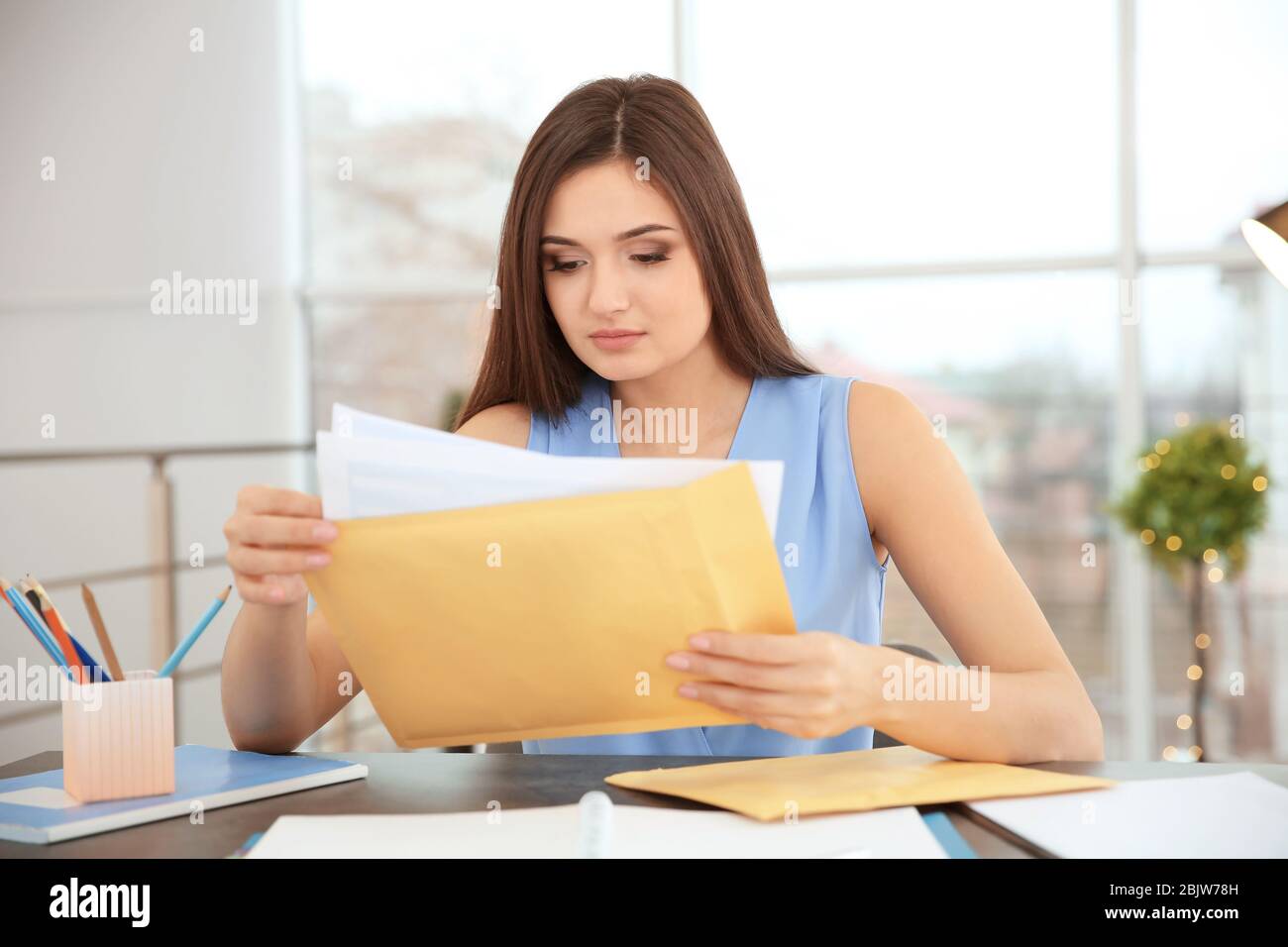 Young woman opening package with parcel indoors Stock Photo - Alamy