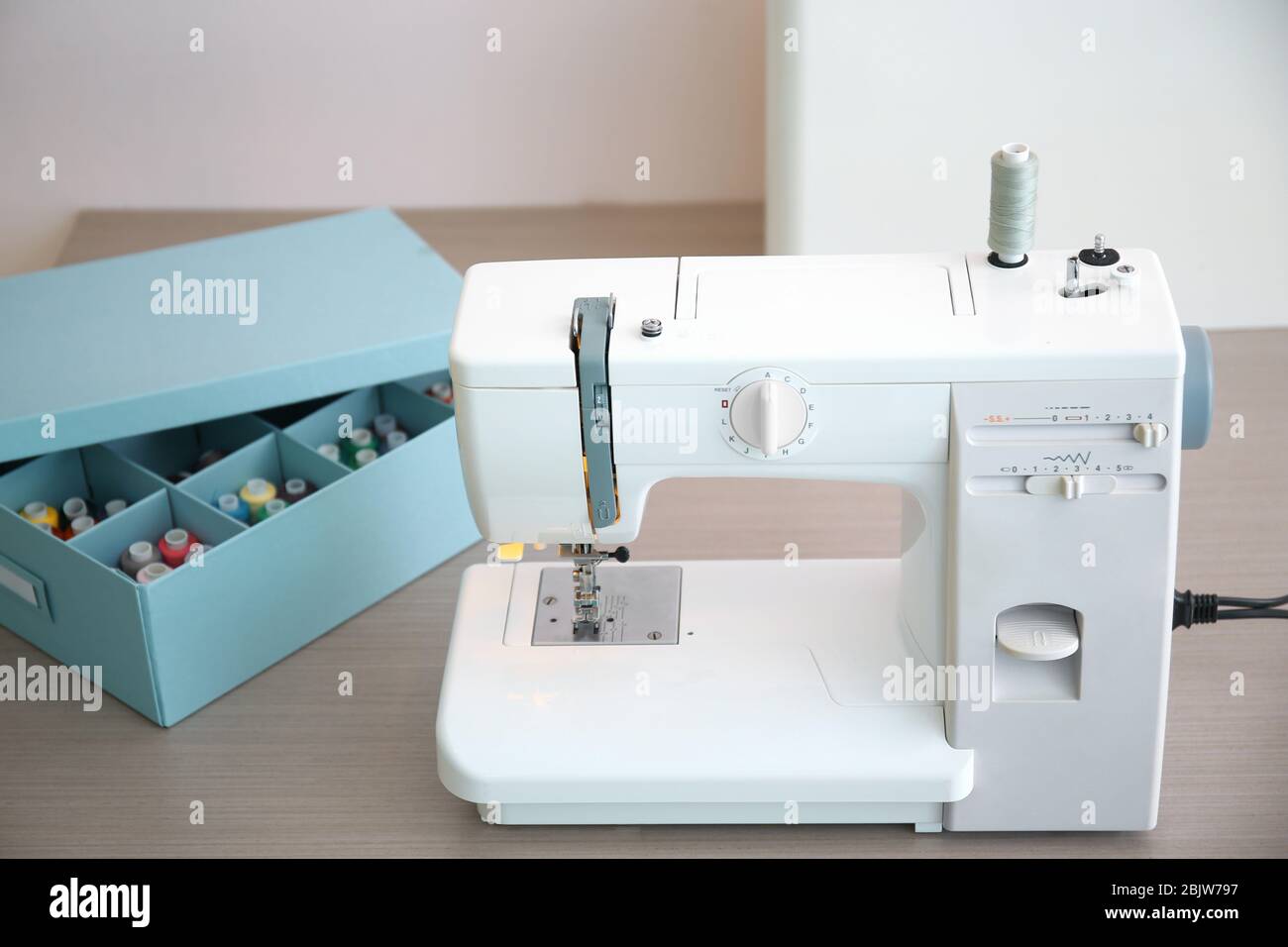 Sewing machine on table in tailor's workshop Stock Photo - Alamy