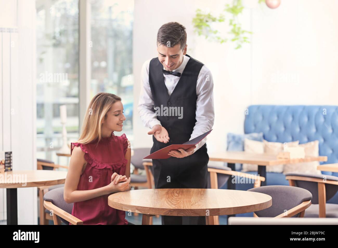 Waiter showing menu to client in restaurant Stock Photo - Alamy