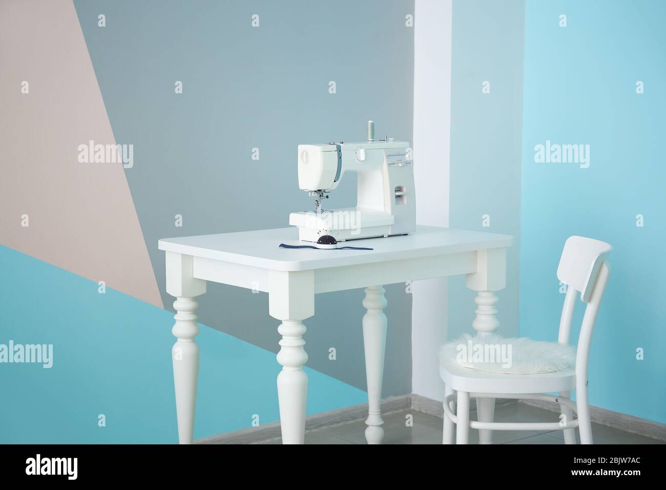 Sewing machine on table in tailor's workshop Stock Photo - Alamy