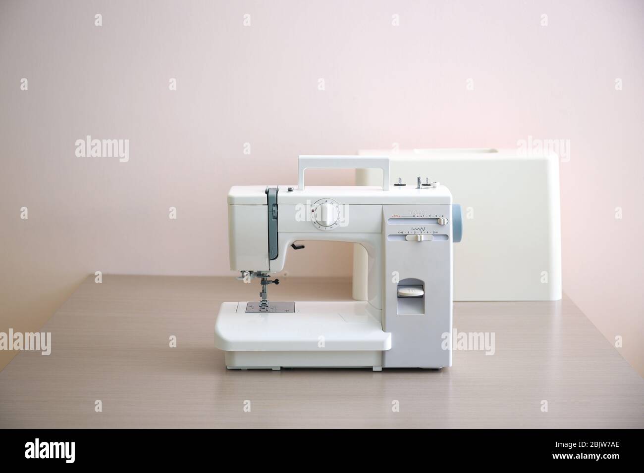 Sewing machine on table in tailor's workshop Stock Photo - Alamy