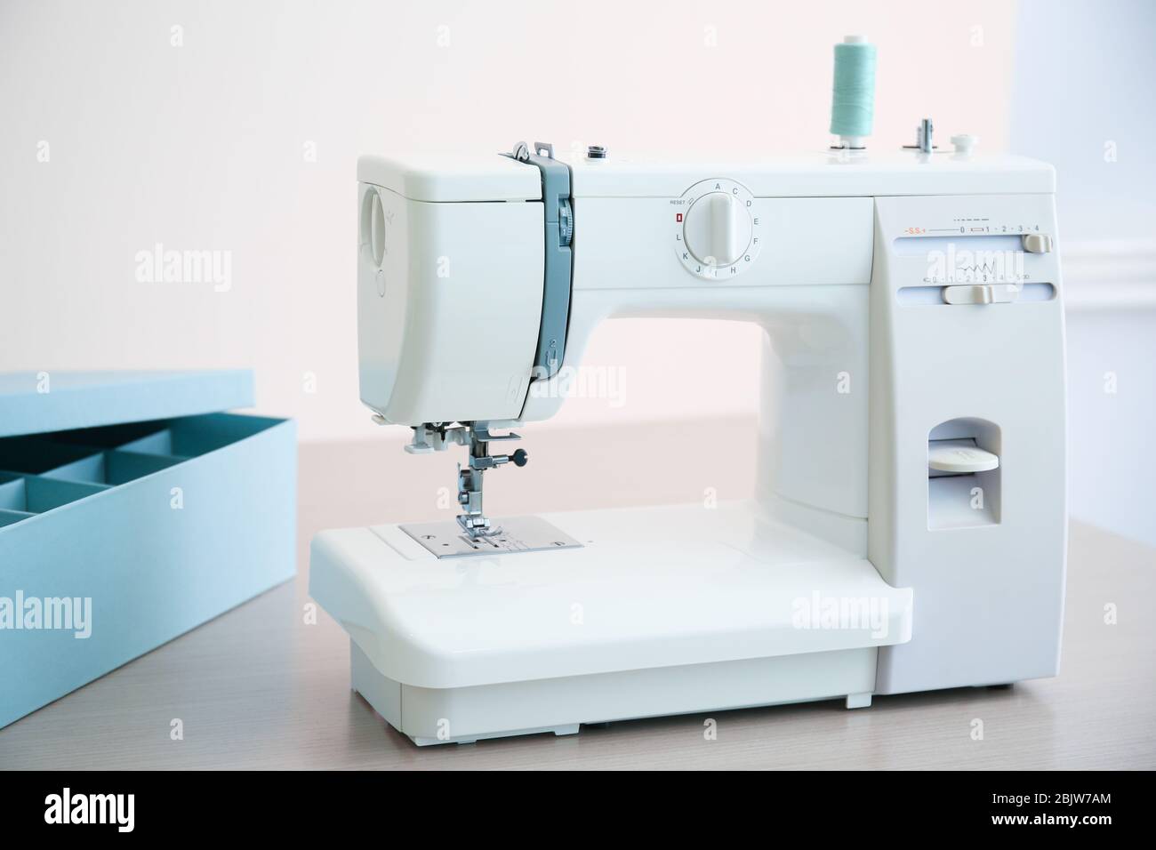 Sewing machine on table in tailor's workshop Stock Photo - Alamy