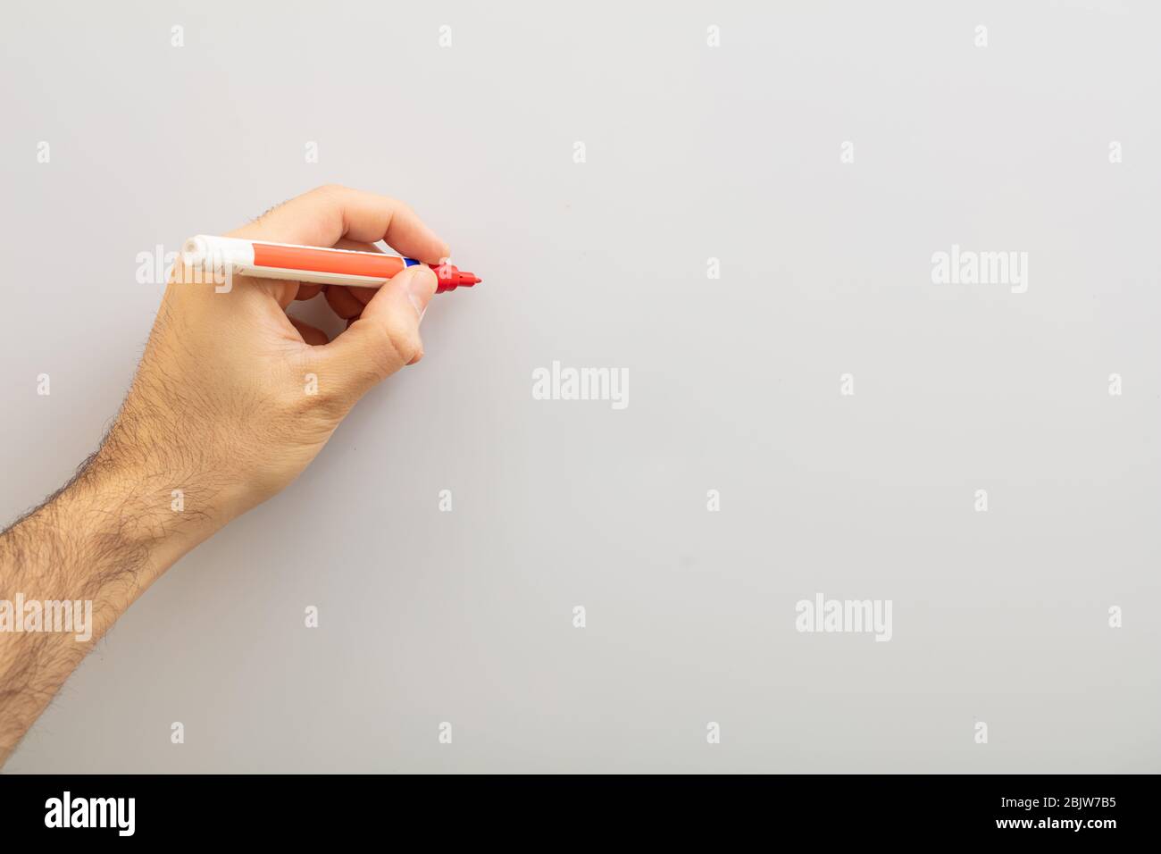 Left hand with a marker isolated on gray background. Left handed man ...