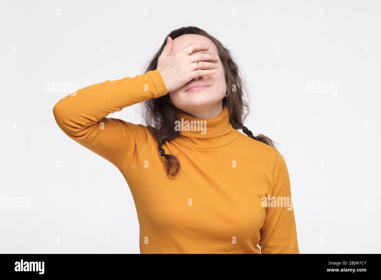 Woman covering in yellow clothes with her hand. Studio shot Stock Photo ...