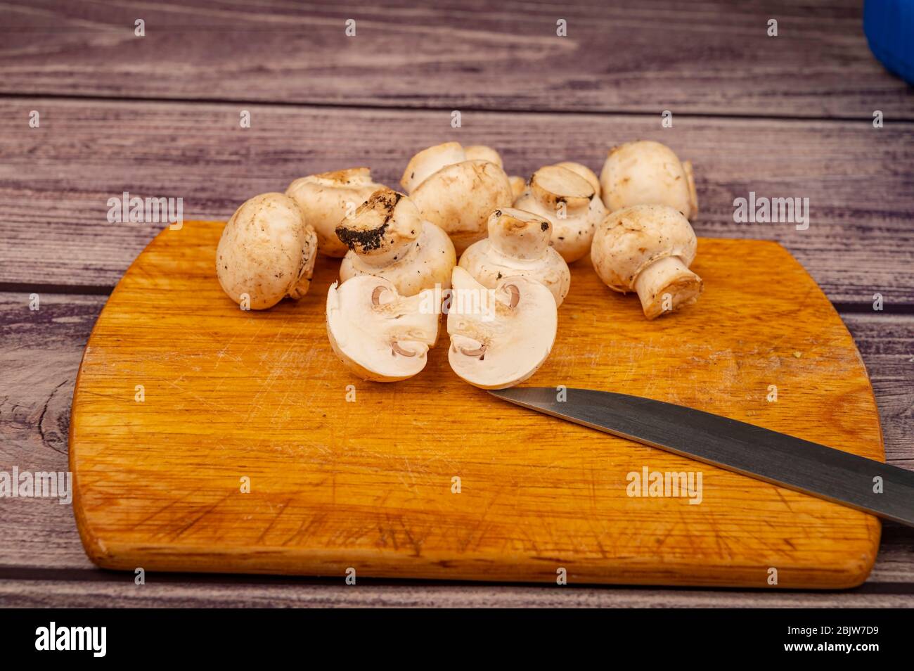 Halves of cut mushrooms and young mushrooms scattered on a wooden ...